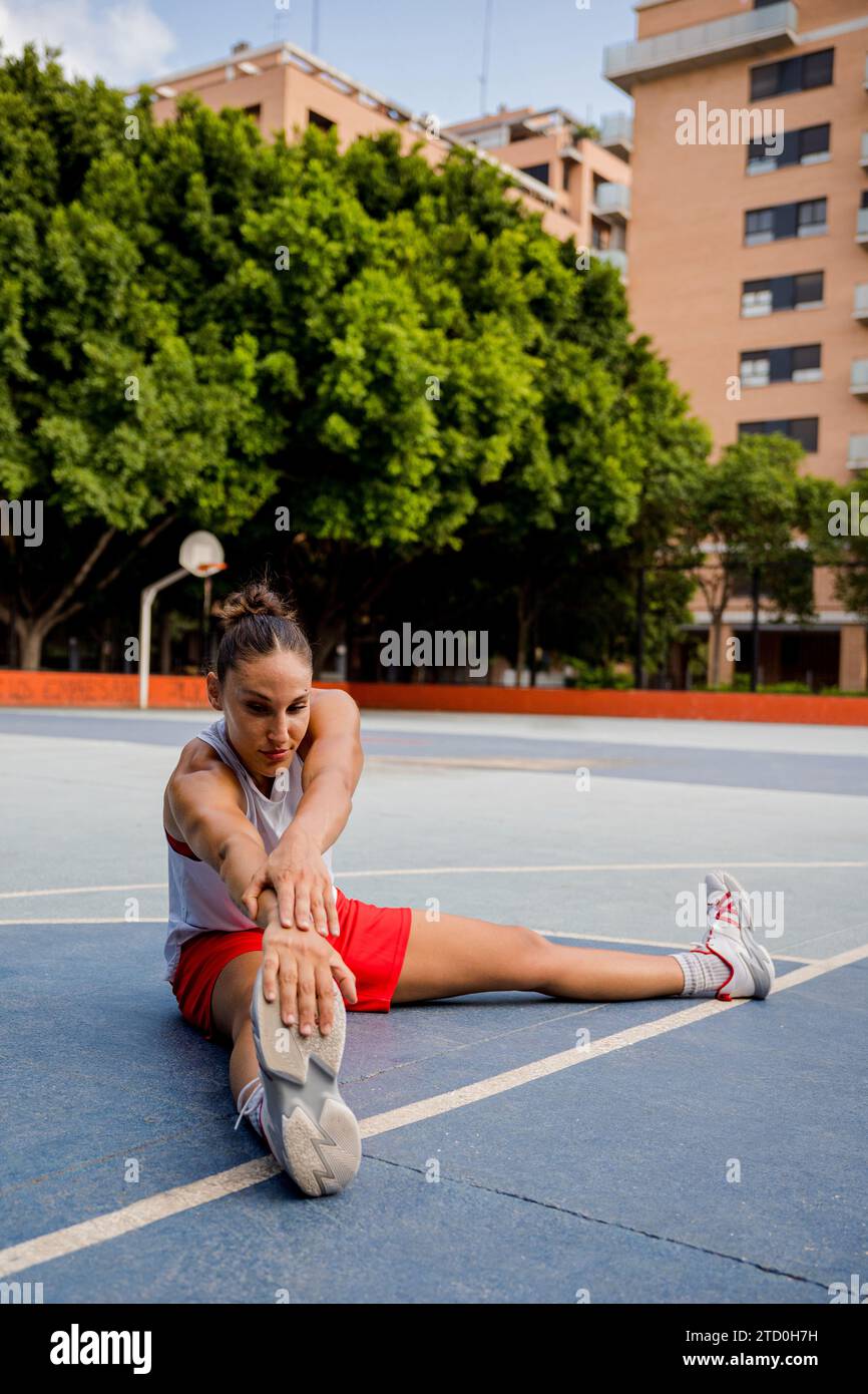 Full body of determined young female basketball player sitting and ...