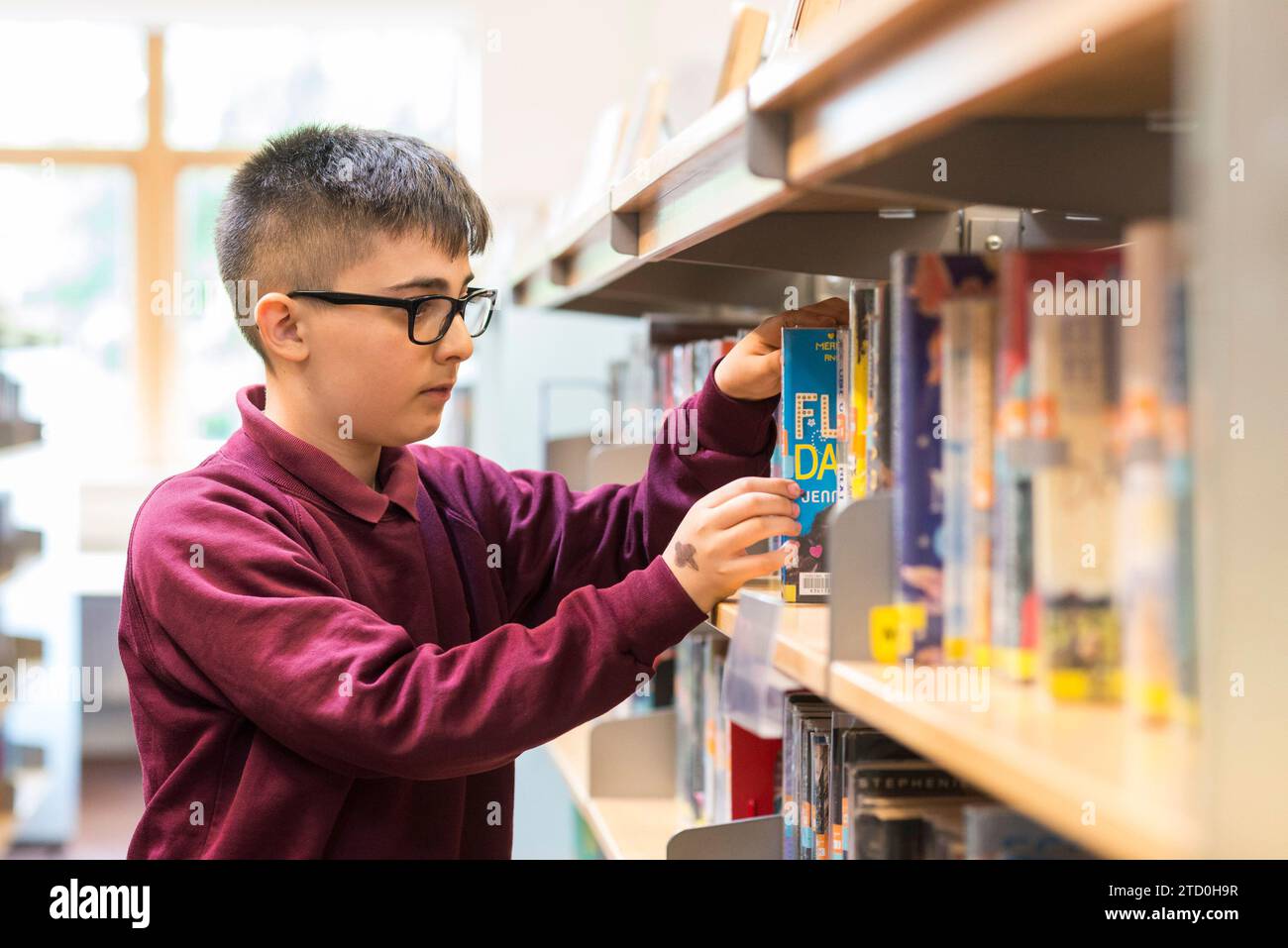 A young student chooses a book to read from the shelves of a school ...