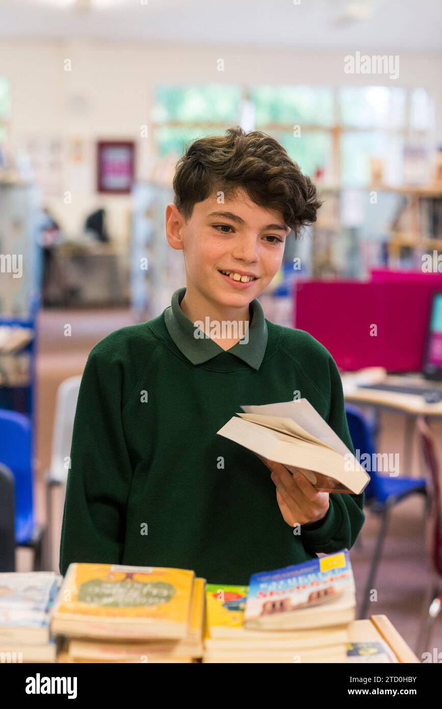 A male student checks out a book at the school library with the ...
