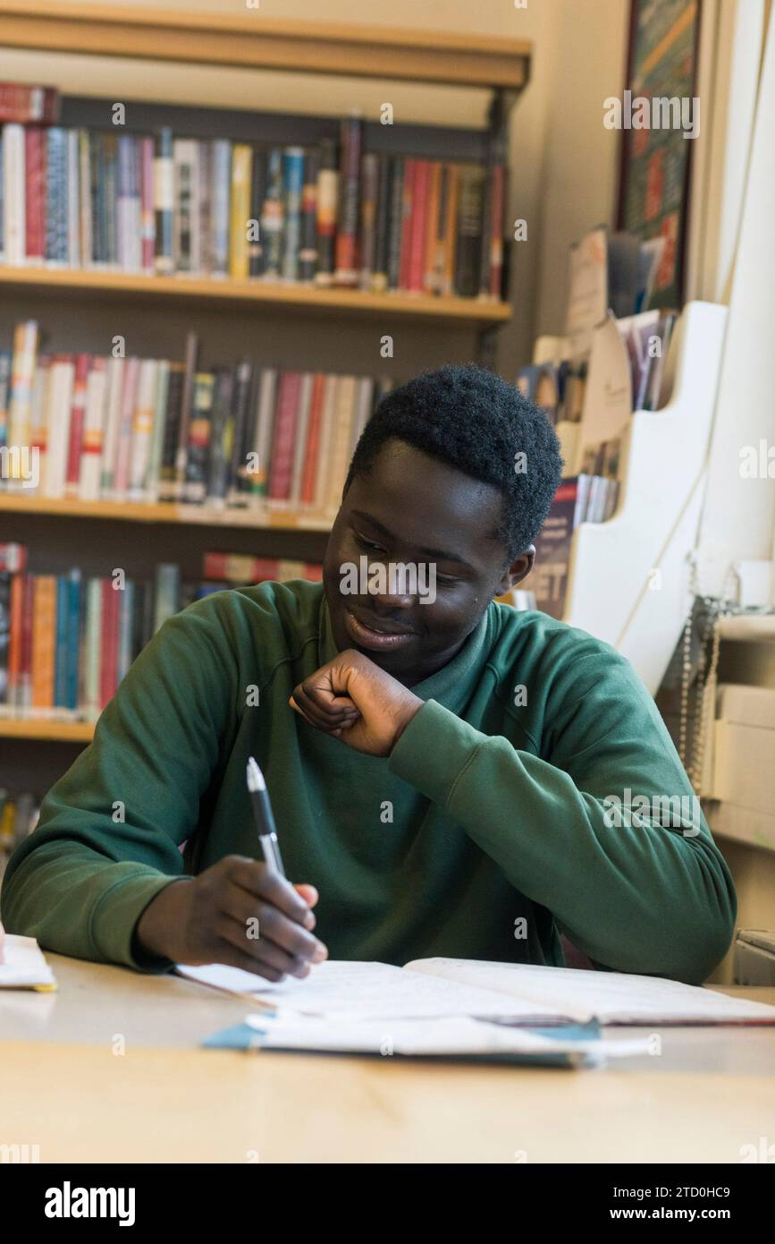 Two boys sit at a desk and work together studying from their workbooks ...