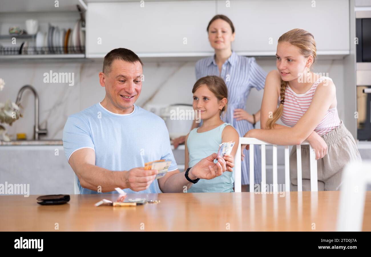 Head of family gives his wife and children pocket money Stock Photo - Alamy