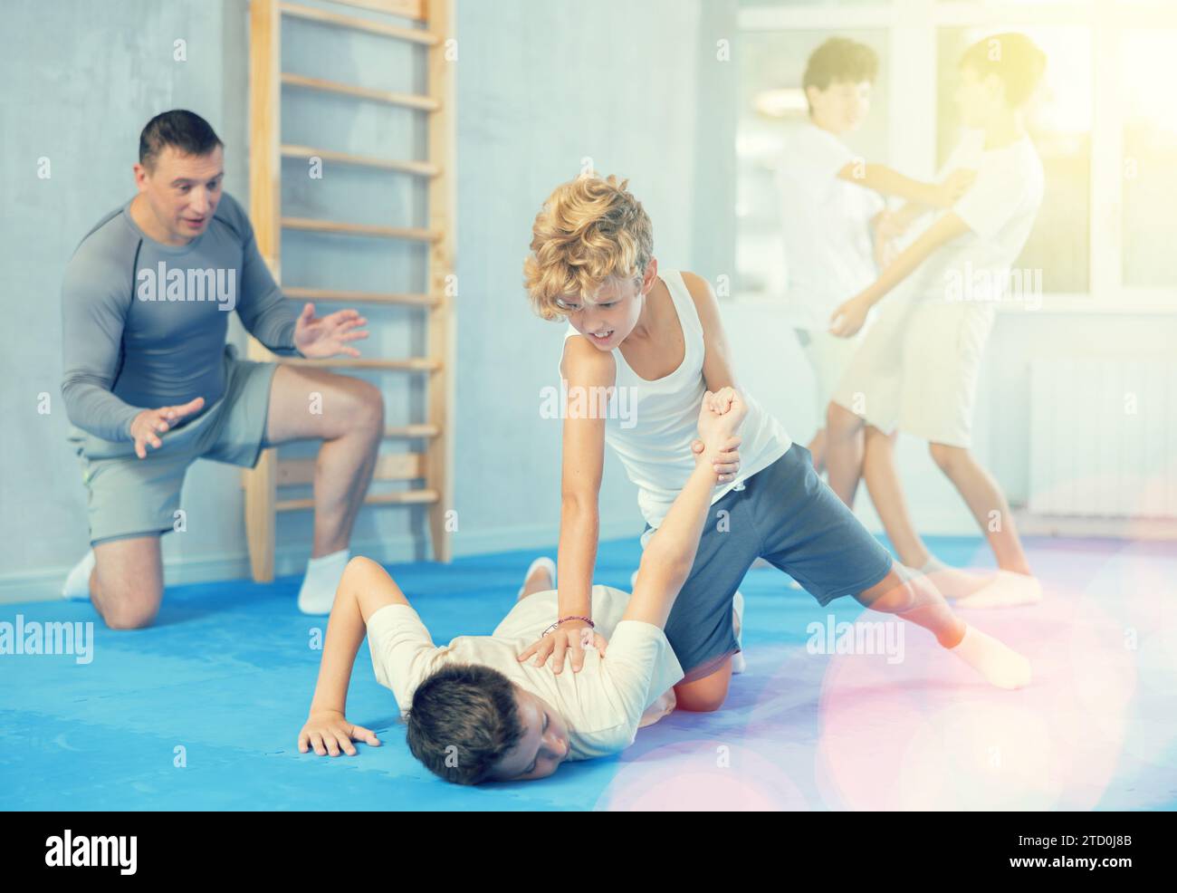 Teenager applying armlock technique to face-down opponent at self ...