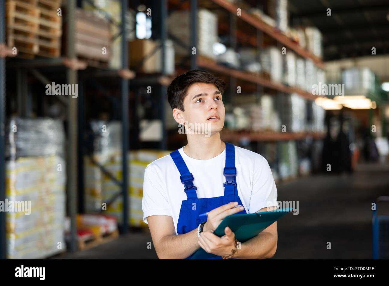 In warehouse of store, guy checks quantity of goods and receipt ...