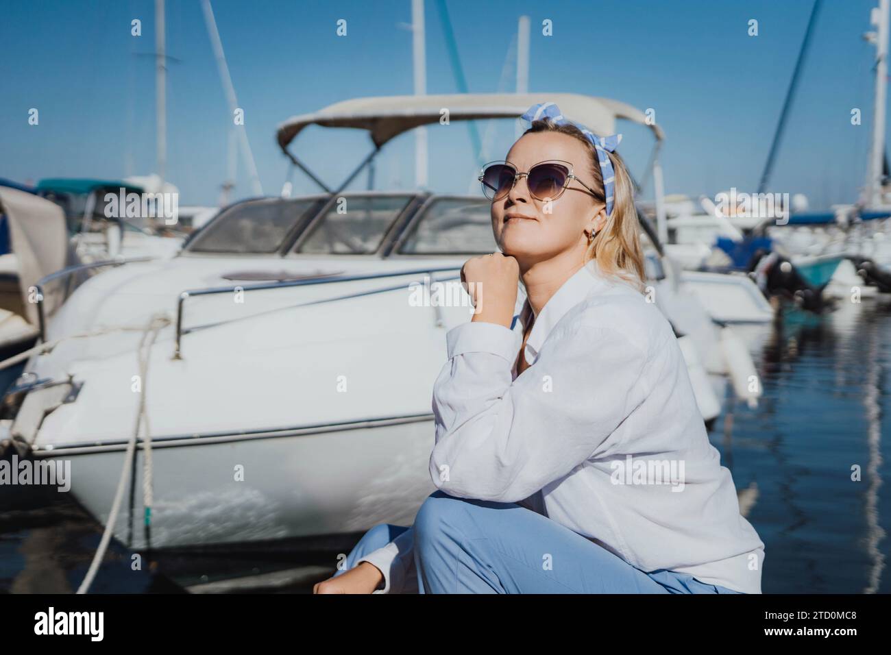 Woman in white shirt in marina , surrounded by several other boats. The ...