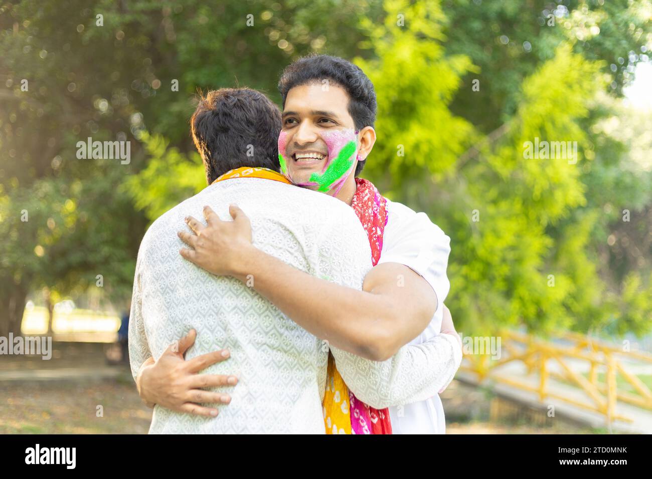 Two young indian men wearing white kurta greeting, hugging each other ...