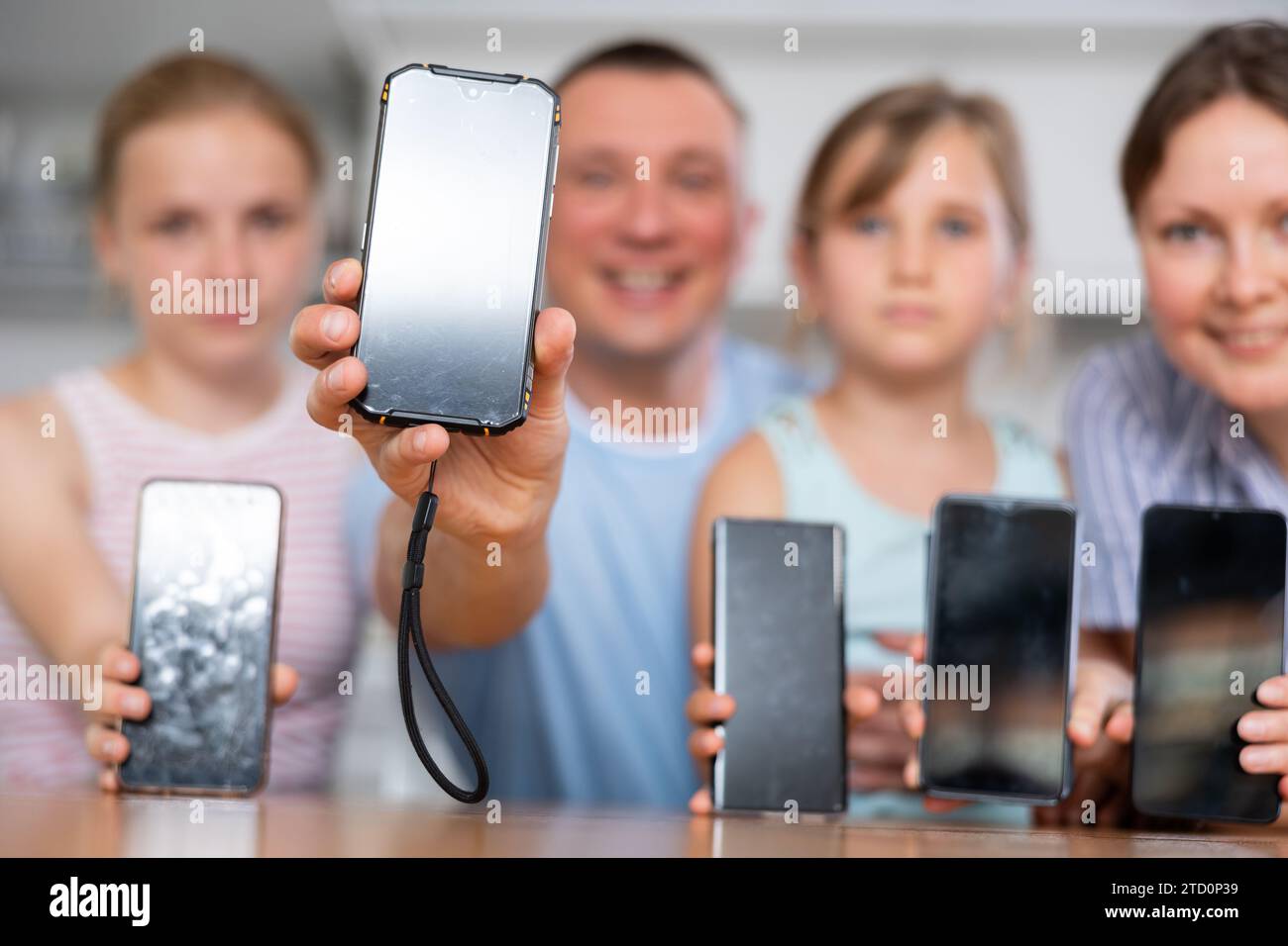 Different smartphones with blank screens in hands of cheerful family ...