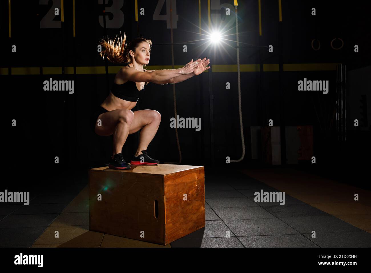 Athletic woman in sportswear jumping on crossfit box in fitness gym ...