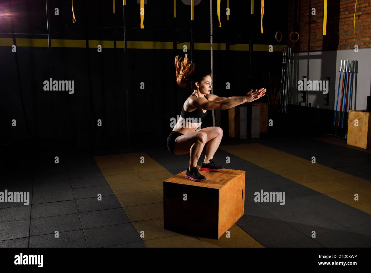 Athletic woman in sportswear jumping on crossfit box in fitness gym ...