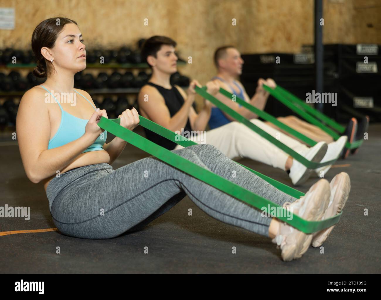 Motivated young woman practicing exercises with stretch rope sitting ...