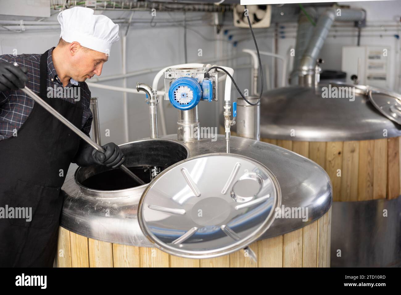 Beer factory worker mixing beer in tank Stock Photo - Alamy