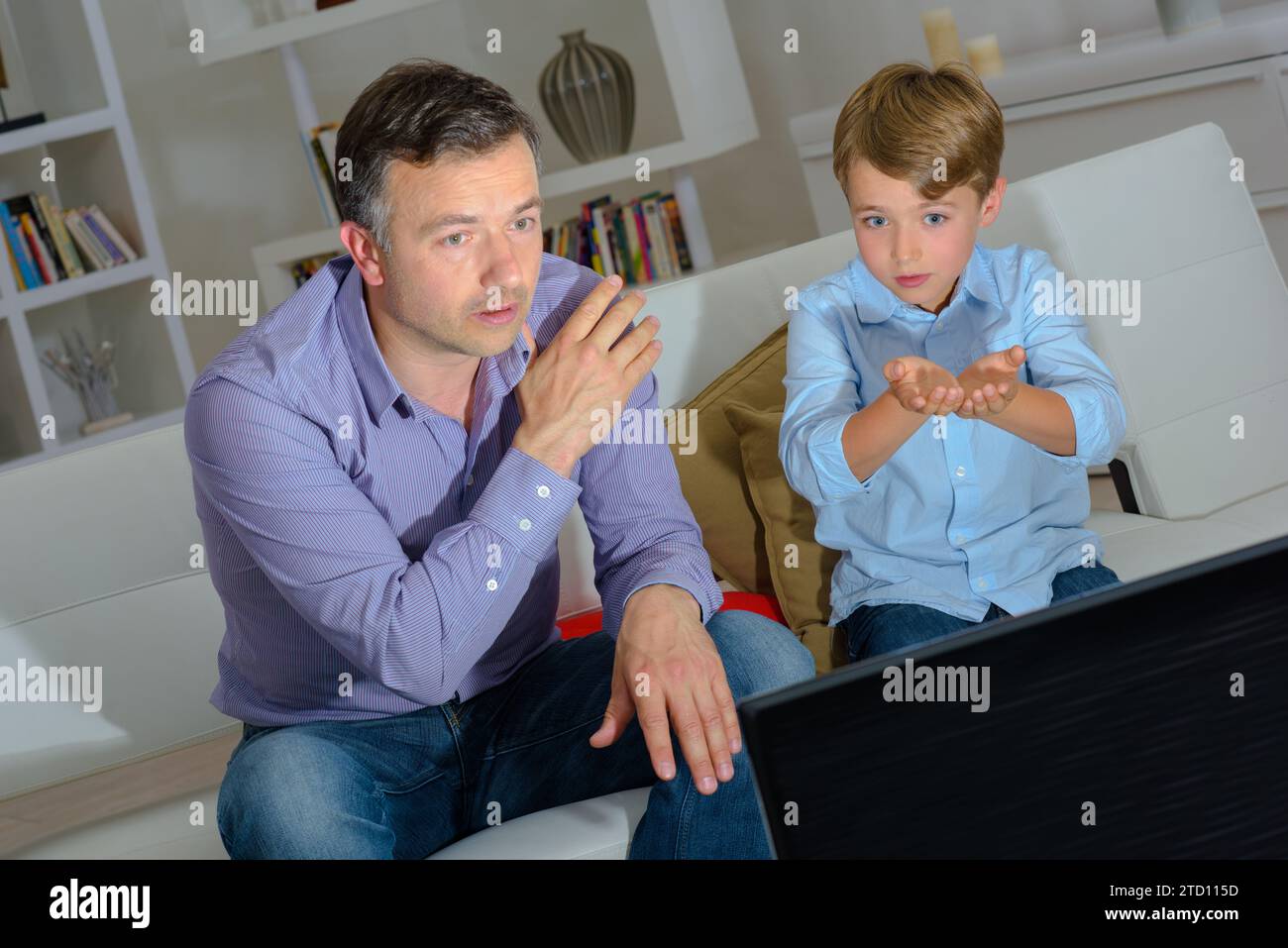 Father telling child to wait while watching television Stock Photo - Alamy