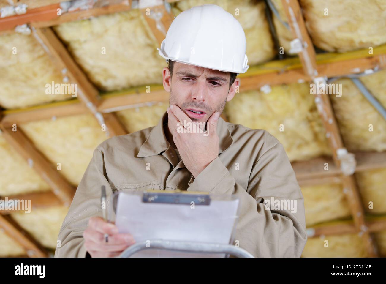 pensive builder standing with clipboard Stock Photo - Alamy