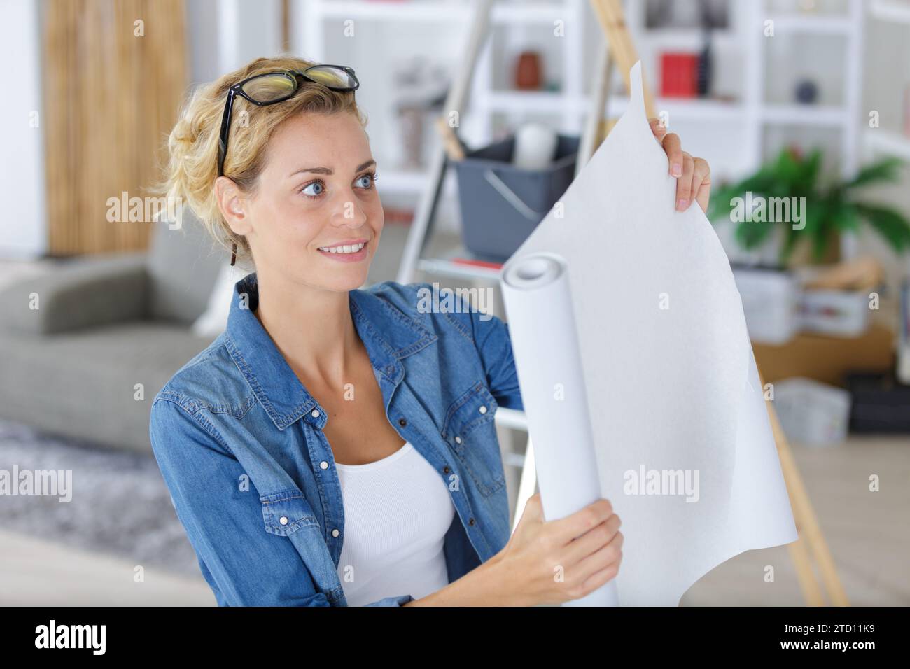 woman unrolling a wall paper on the wall Stock Photo - Alamy