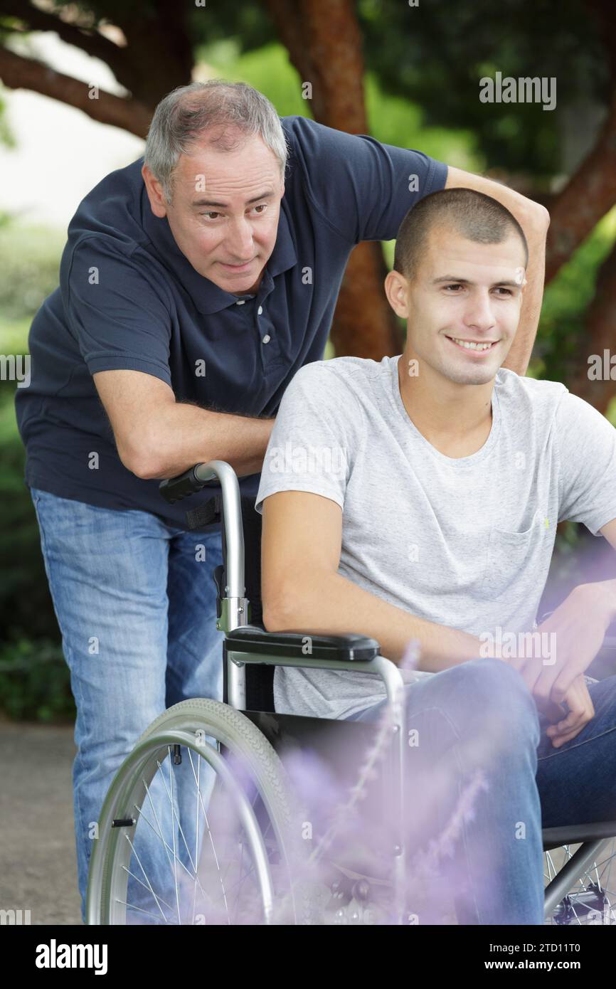 male carer with young handicapped on a wheelchair Stock Photo - Alamy