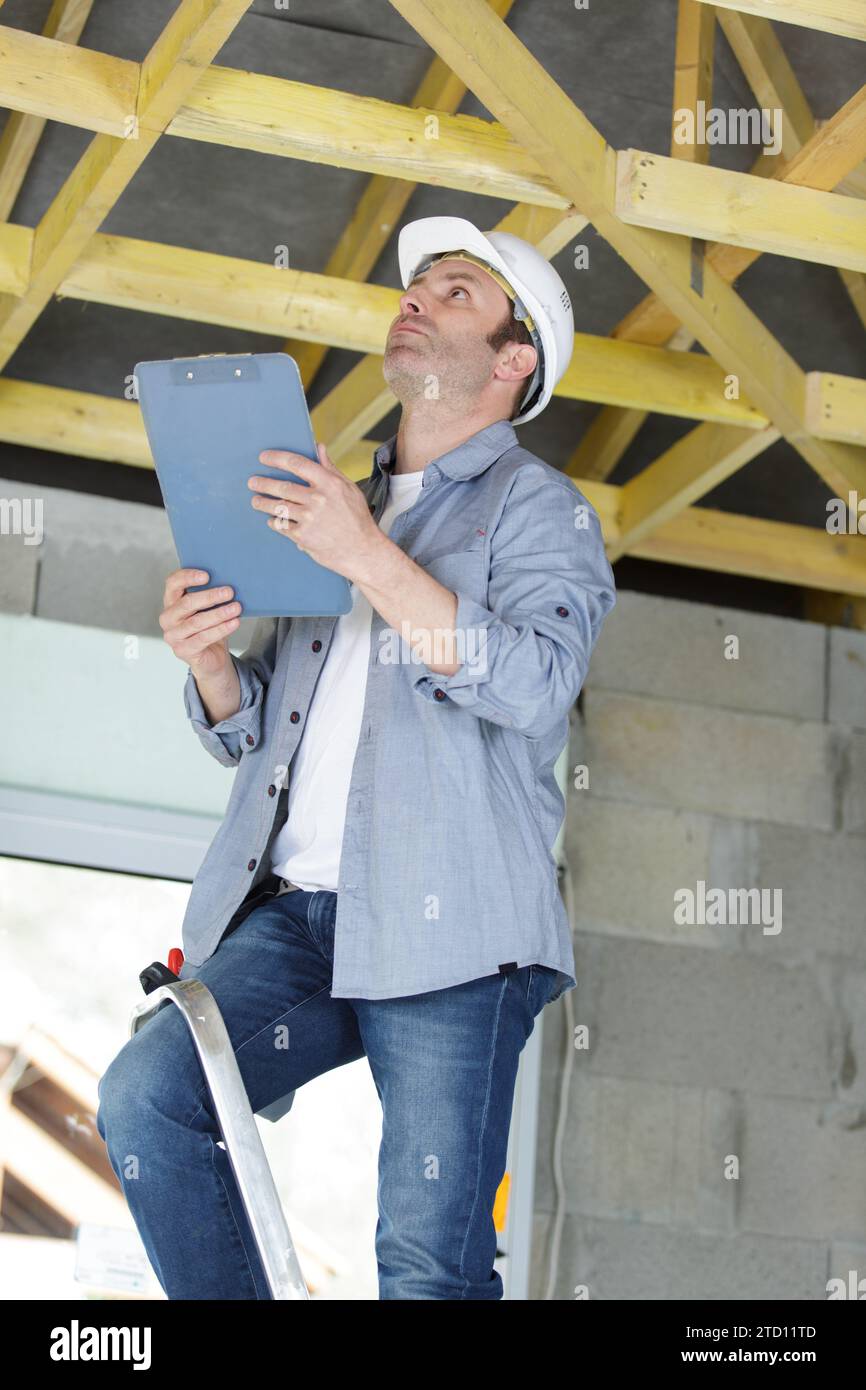 foreman in hard hat holding clipboard on a ladder Stock Photo - Alamy