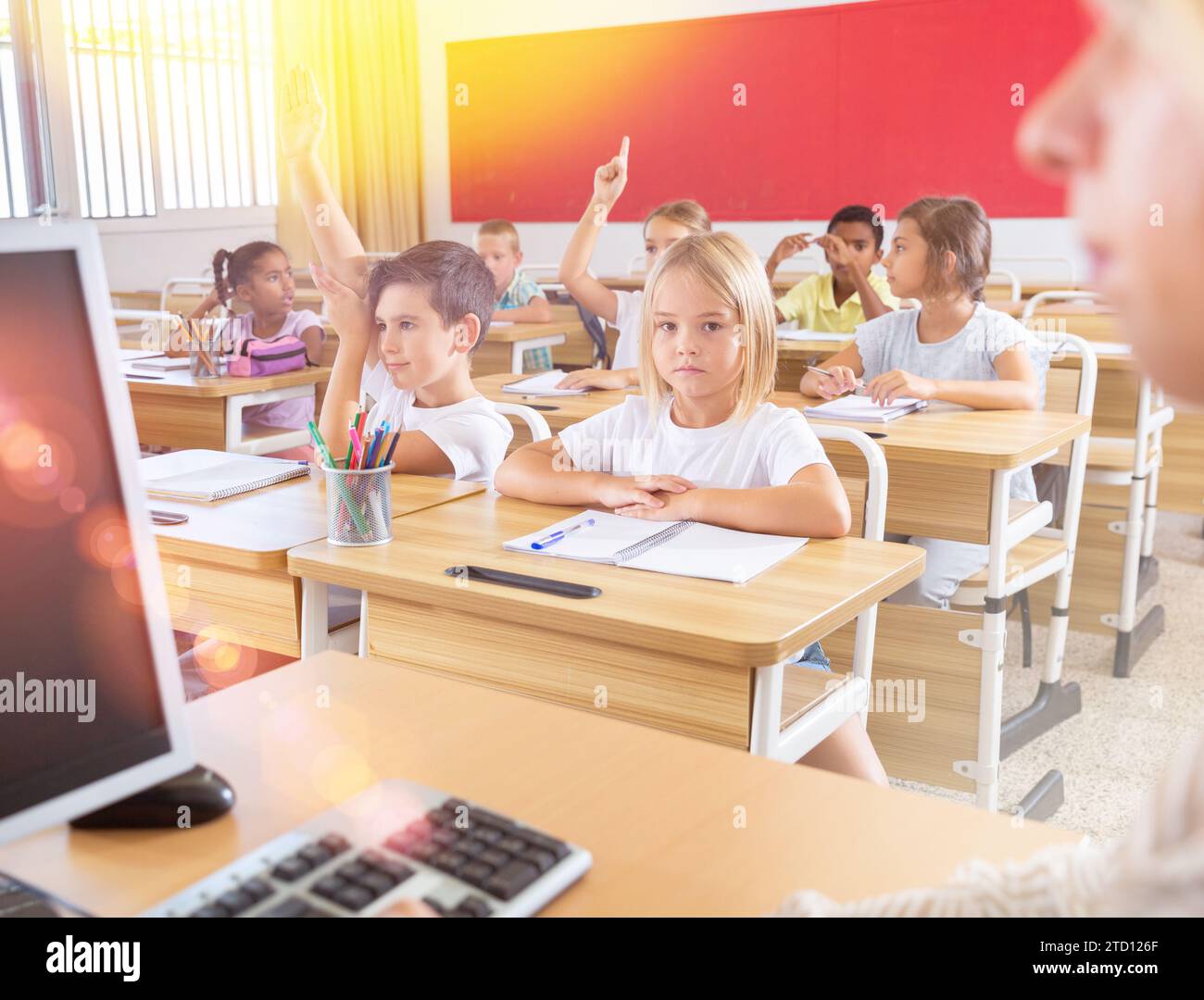 Diligent towheaded preteen girl looking at camera during lesson Stock ...
