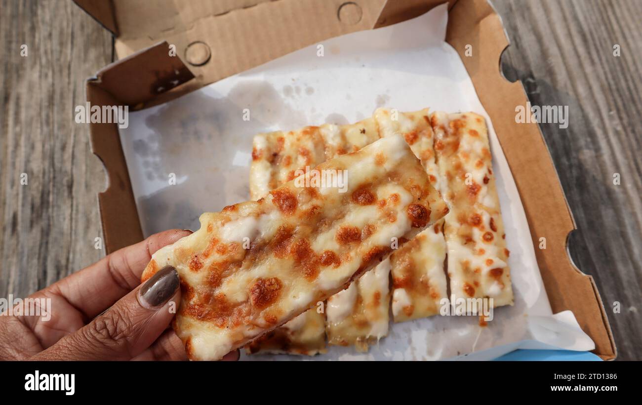 Female holding eating Cheesy garlic Pizza Bread sticks. Baked cheese ...