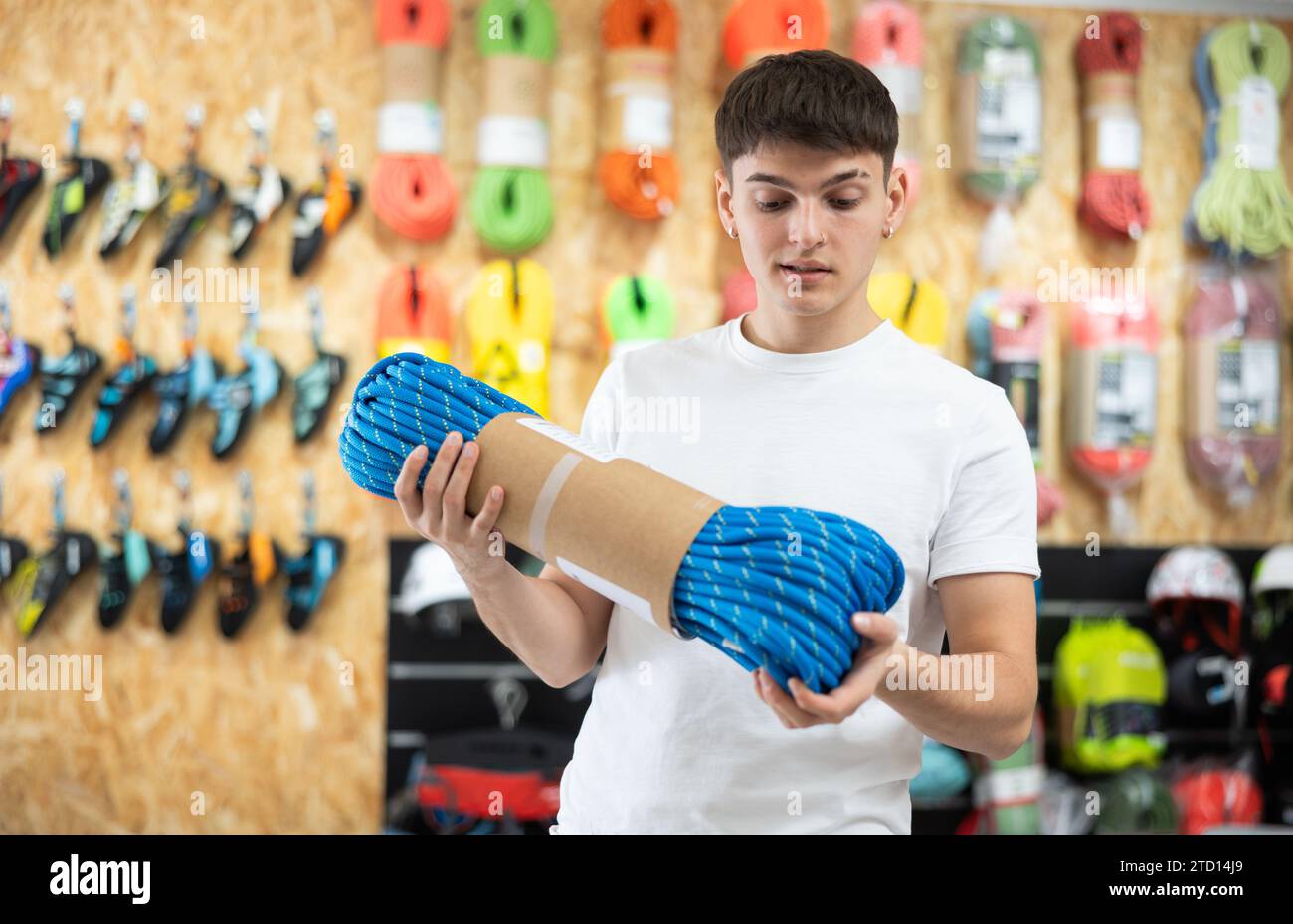 Young guy carefully selects climbing rope for a hike in sports ...