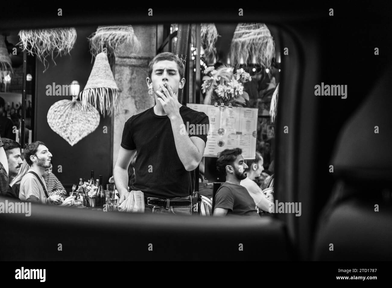 Young man smoking in the streets of Paris, seen from inside a car ...