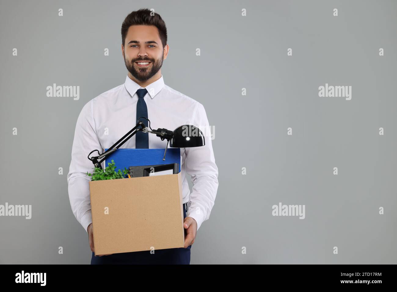 Happy unemployed man with box of personal office belongings on light ...