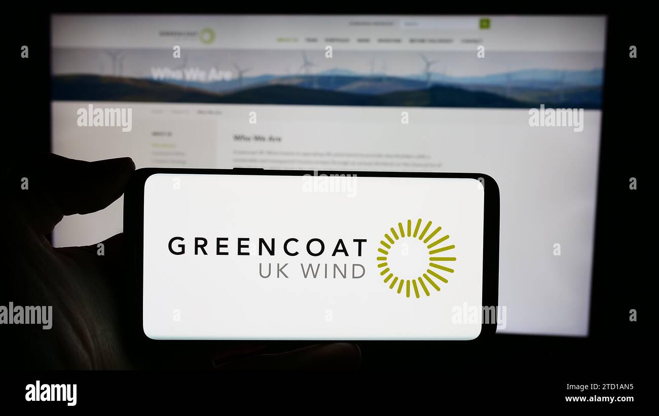 Person holding cellphone with logo of British investment company Greencoat UK Wind plc in front ...