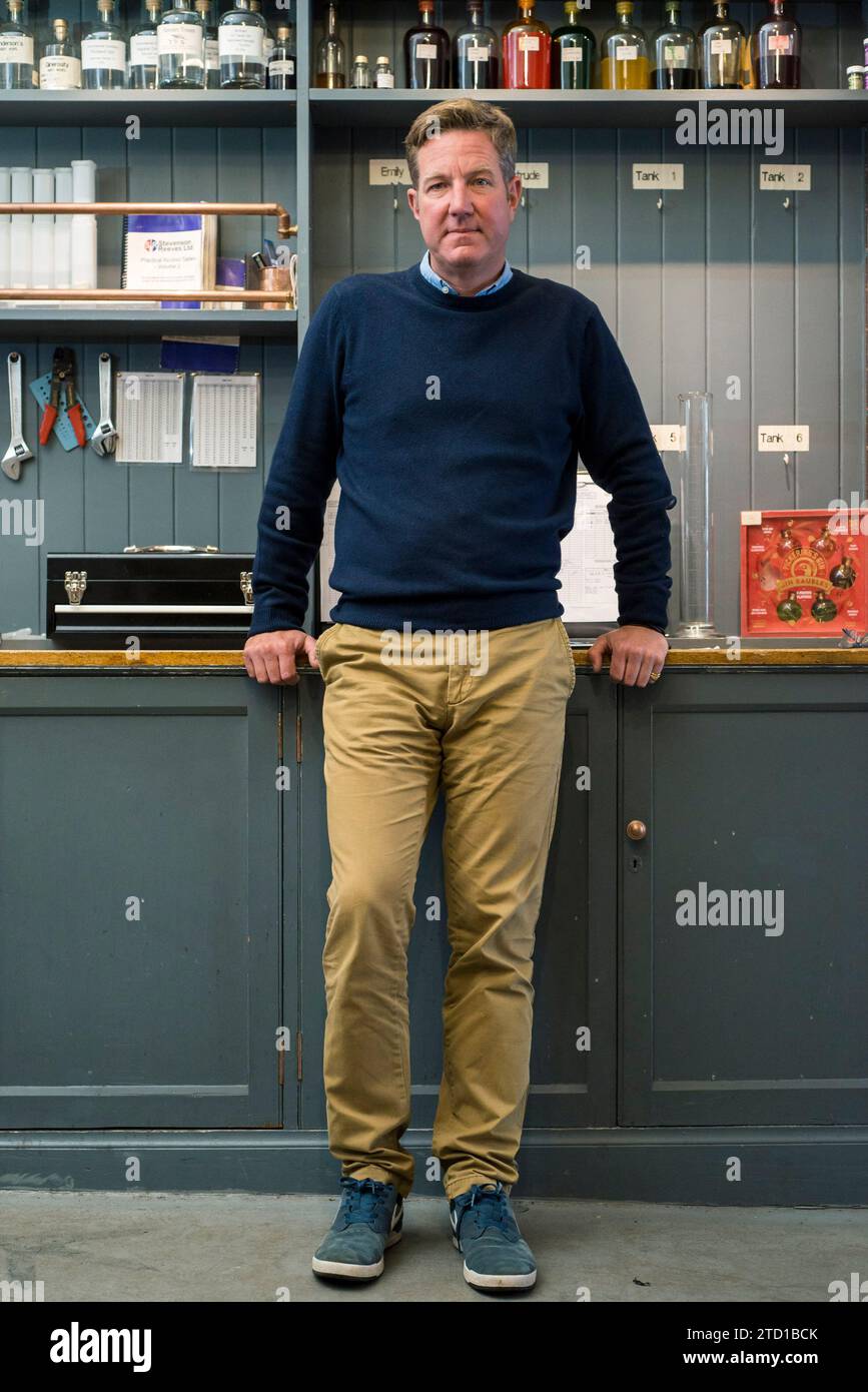 A male small business owner stands with his gin making equipment in an ...