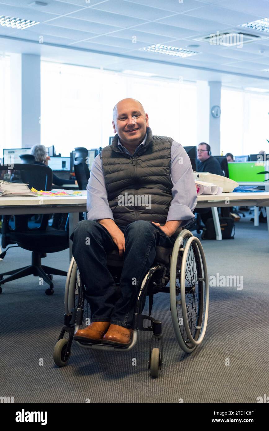 A man in a wheelchair is in his IT tech office which has good ...
