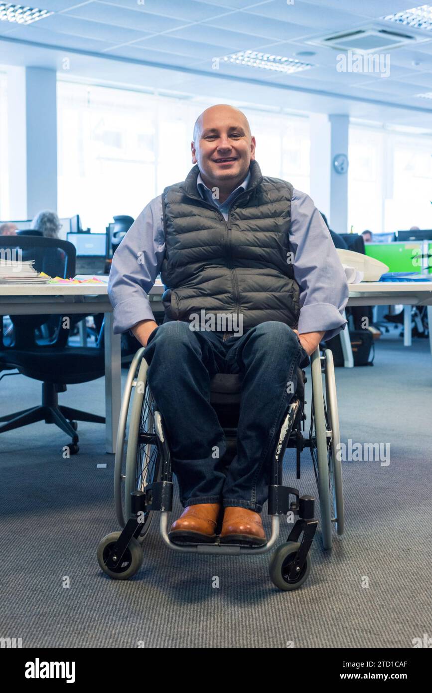 A man in a wheelchair is in his IT tech office which has good ...