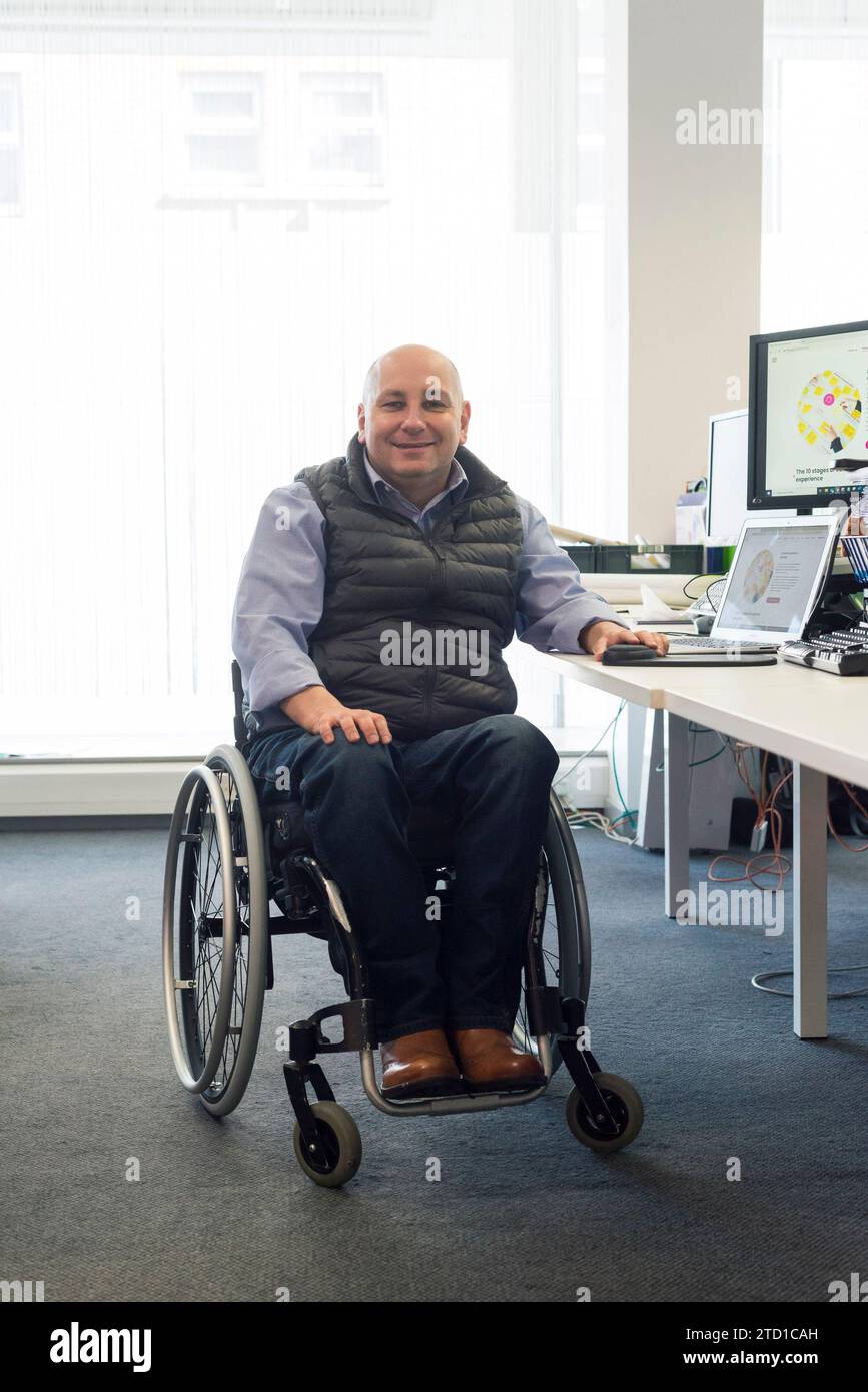 A man in a wheelchair is in his IT tech office which has good ...