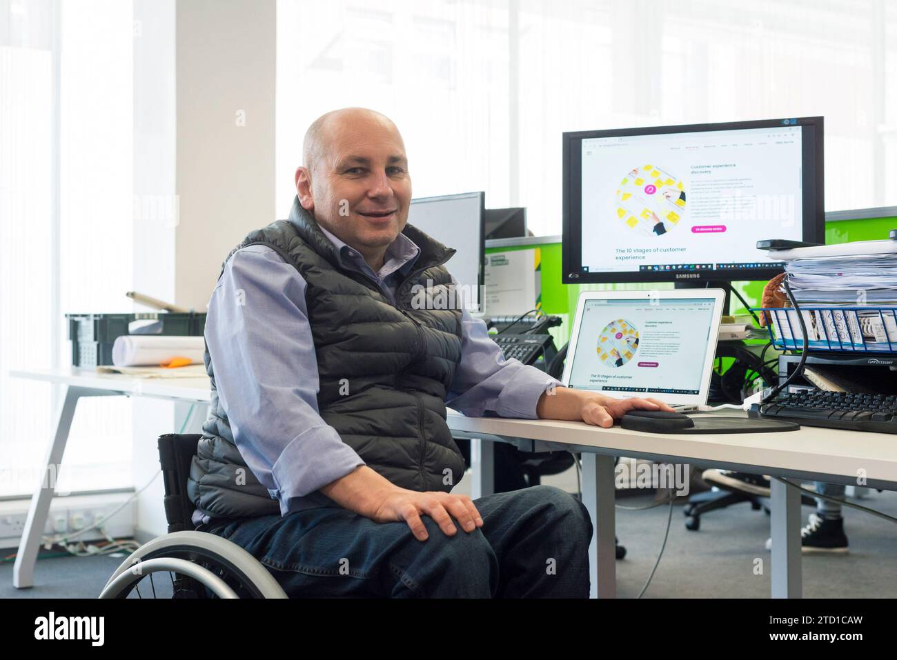 A man in a wheelchair is in his IT tech office which has good ...
