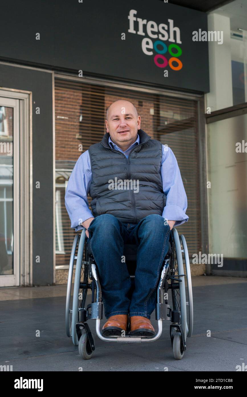 A man in a wheelchair is in his IT tech office which has good ...