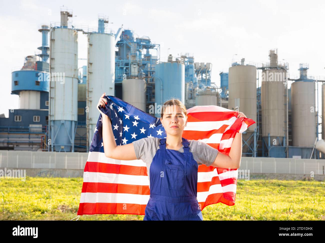Sad young woman near factory with USA flag Stock Photo - Alamy