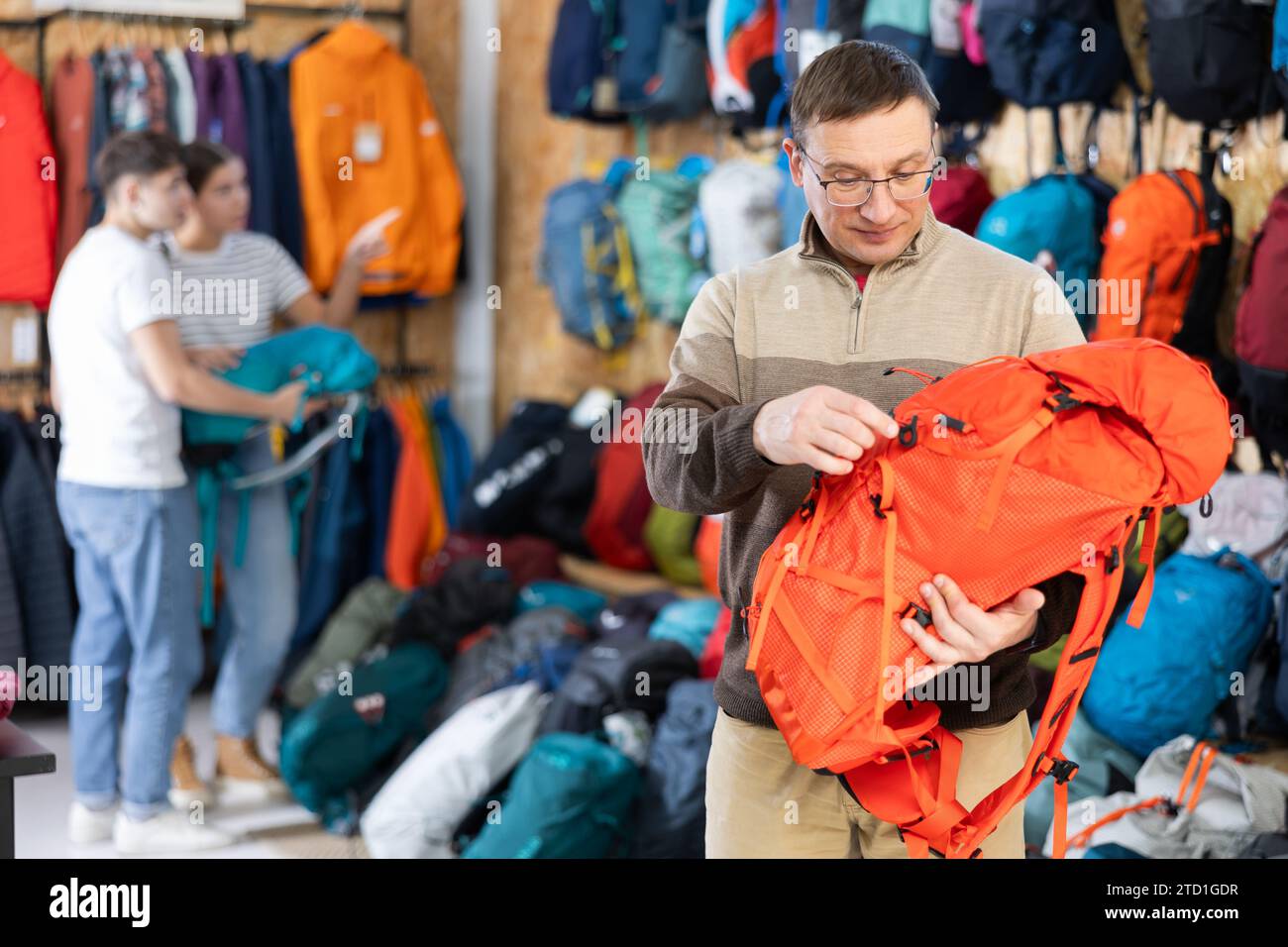 Buyer man chooses autumn backpack in store for hikes Stock Photo - Alamy