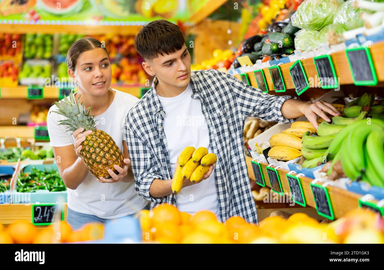 Young husband and wife choose fresh fruit together in grocery ...