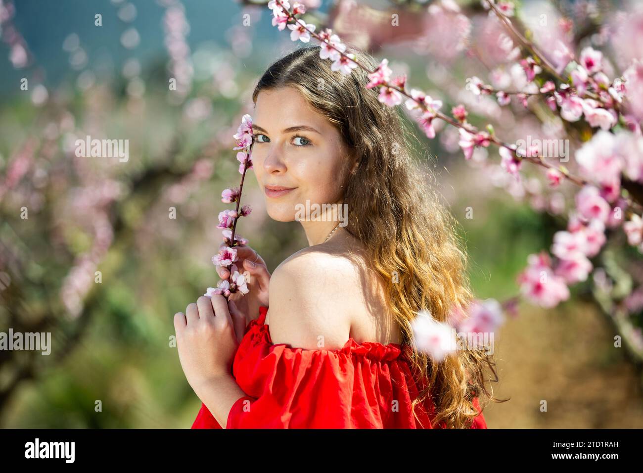 Lady wearing red dress and posing in park with blooming trees Stock ...