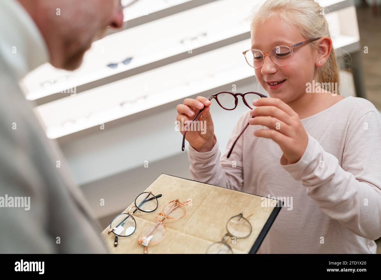 Young girl trying on glasses. She is looking at eyewear selection in ...