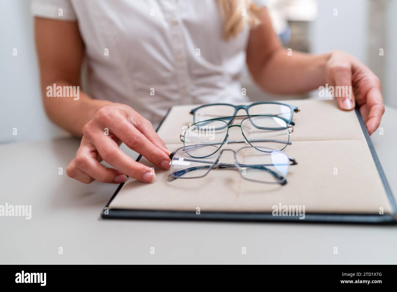 saleswomans hands adjusting eyeglasses on a display tray. focus on ...
