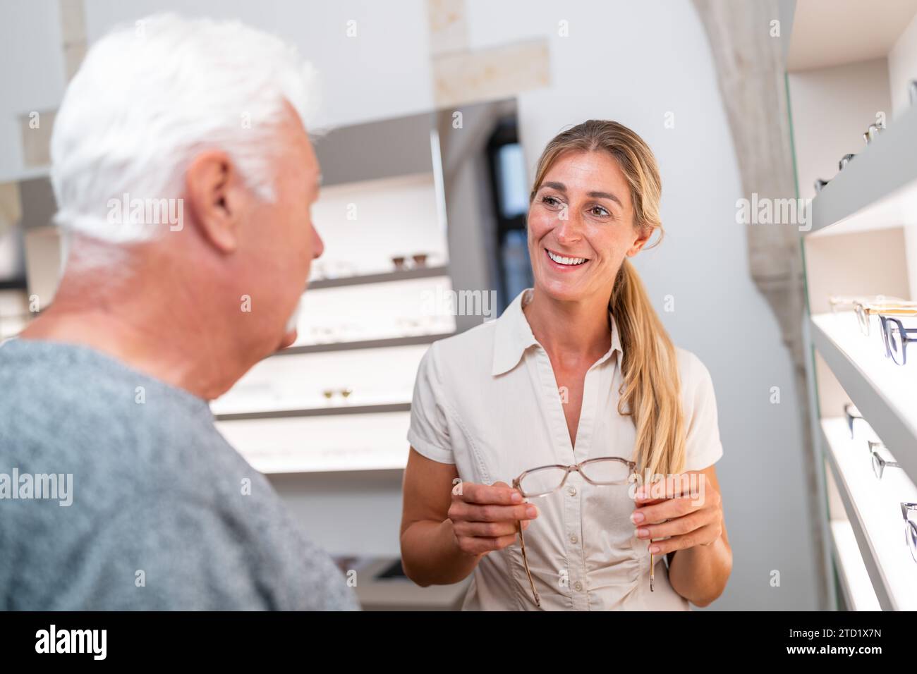Optician showing new glasses to a senior male customer. focus on woman with eyewear in optical ...