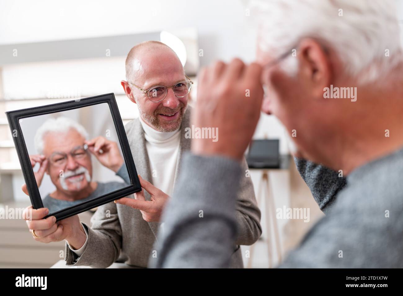Optician holding mirror while senior female customer looking Stock ...