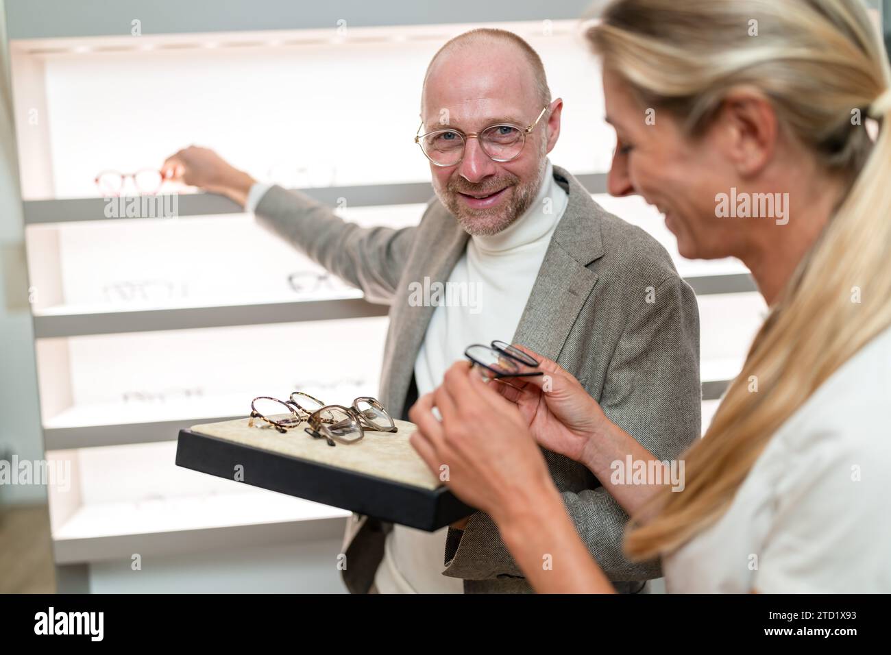 Optician helping a happy customer with glasses selection. Optician is ...