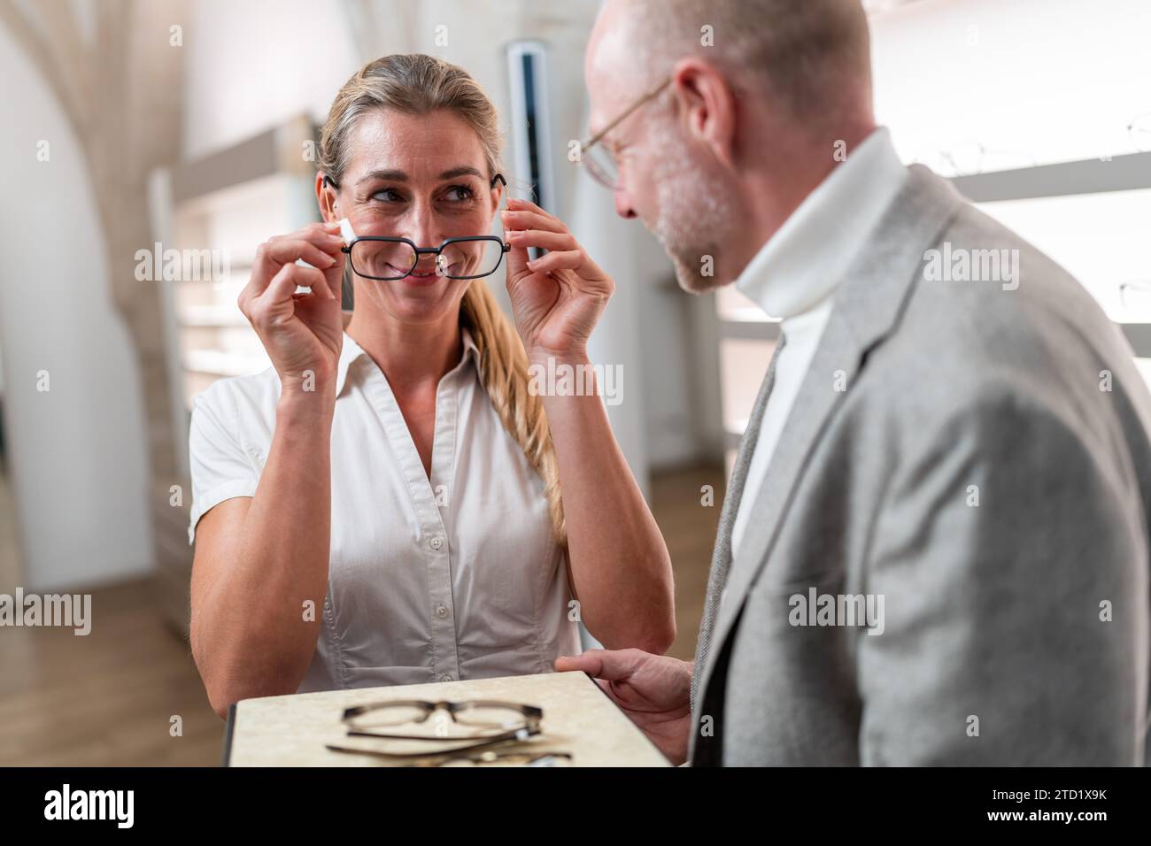 Optician showing glasses to female customer that tries it on. The focus ...