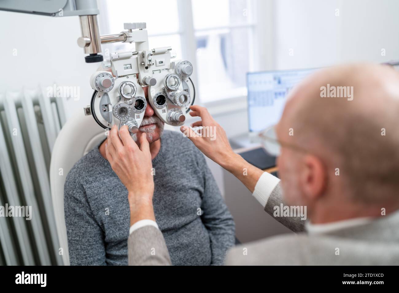 Optometrist adjusting phoropter for senior patient's vision test at the ...
