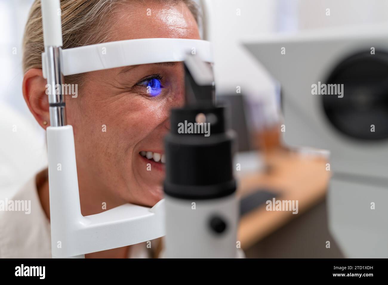 Smiling woman during eye exam with retinal reflection visible using a ...