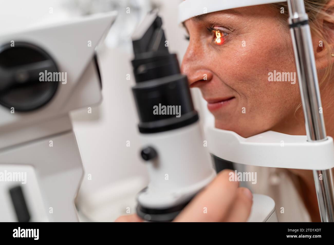 Woman undergoing an eye examination with a focus on her illuminated eye ...