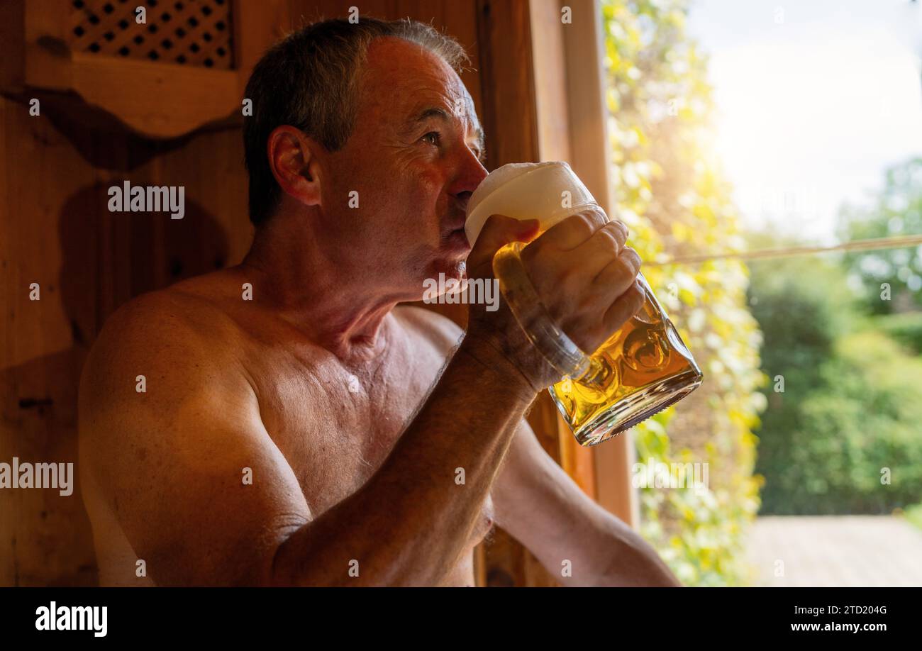 Man drinking german beer in bavarian sauna, sunlight through window ...