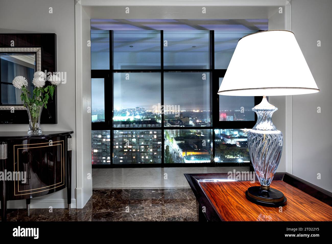 A floor lamp on a table in front of a panoramic window overlooking the ...