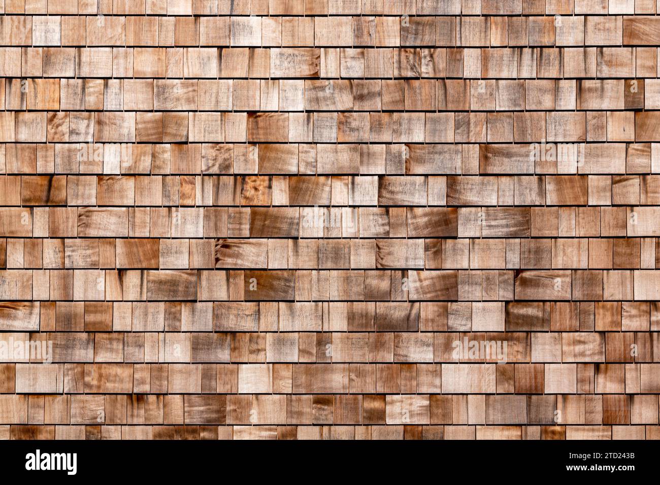 House wall covered with small wooden tiles as a background. Old brown rustic dark brown wooden ...