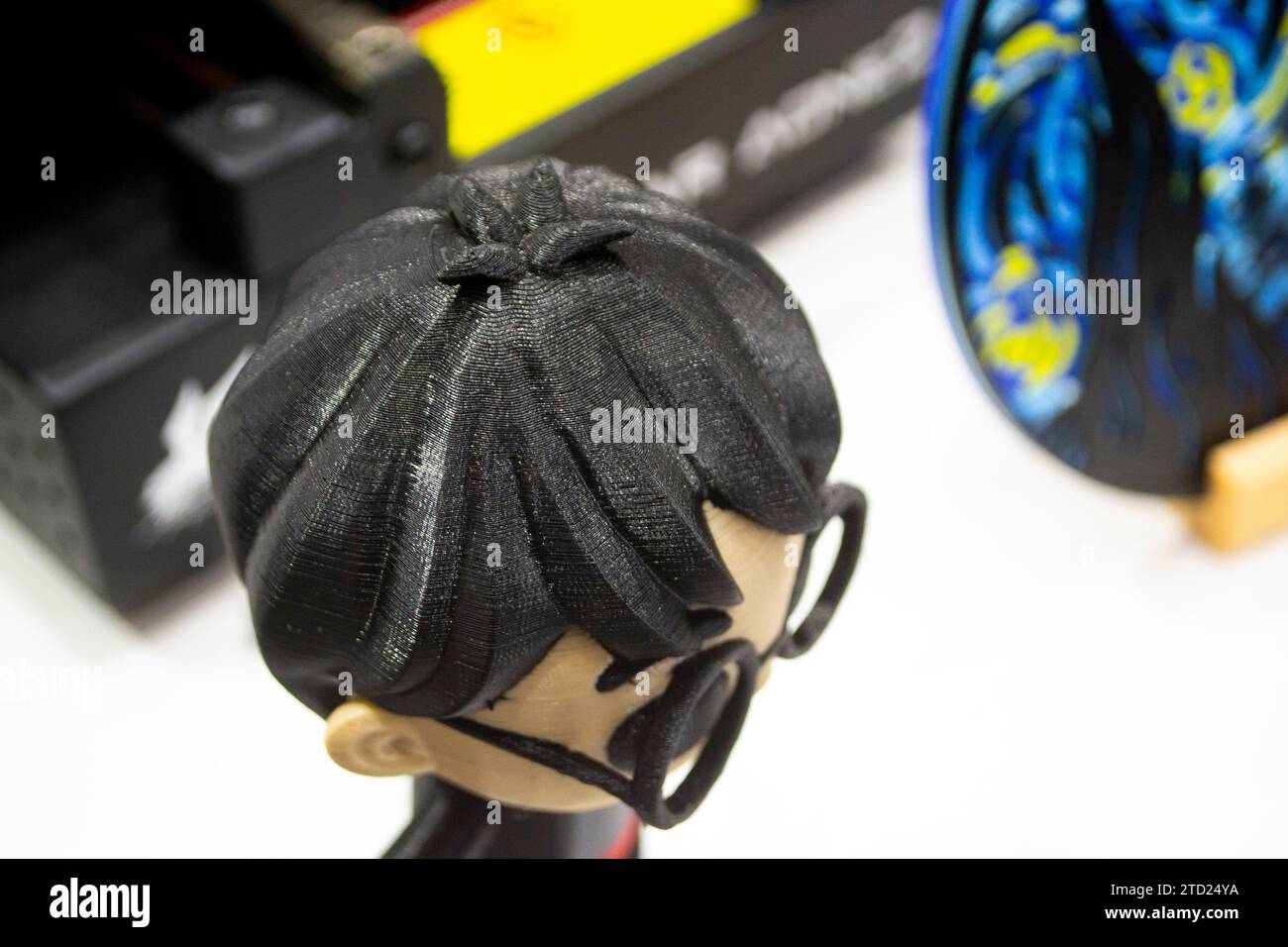 Prototype of head with black hair 3D printed from melted plastic. Close ...