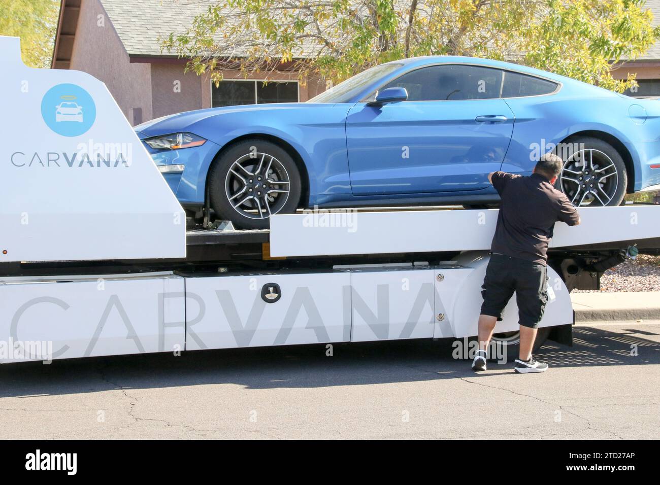 A Carvana representative securely fastens a car sold on-the-spot onto a ...