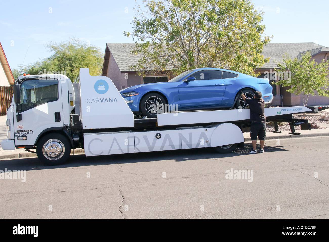 A Carvana representative securely fastens a car sold on-the-spot onto a ...